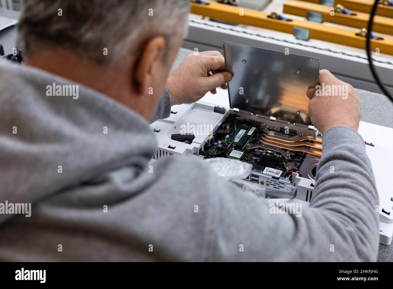 Photo of an adult man in a gray sweater who assembles a computer ...