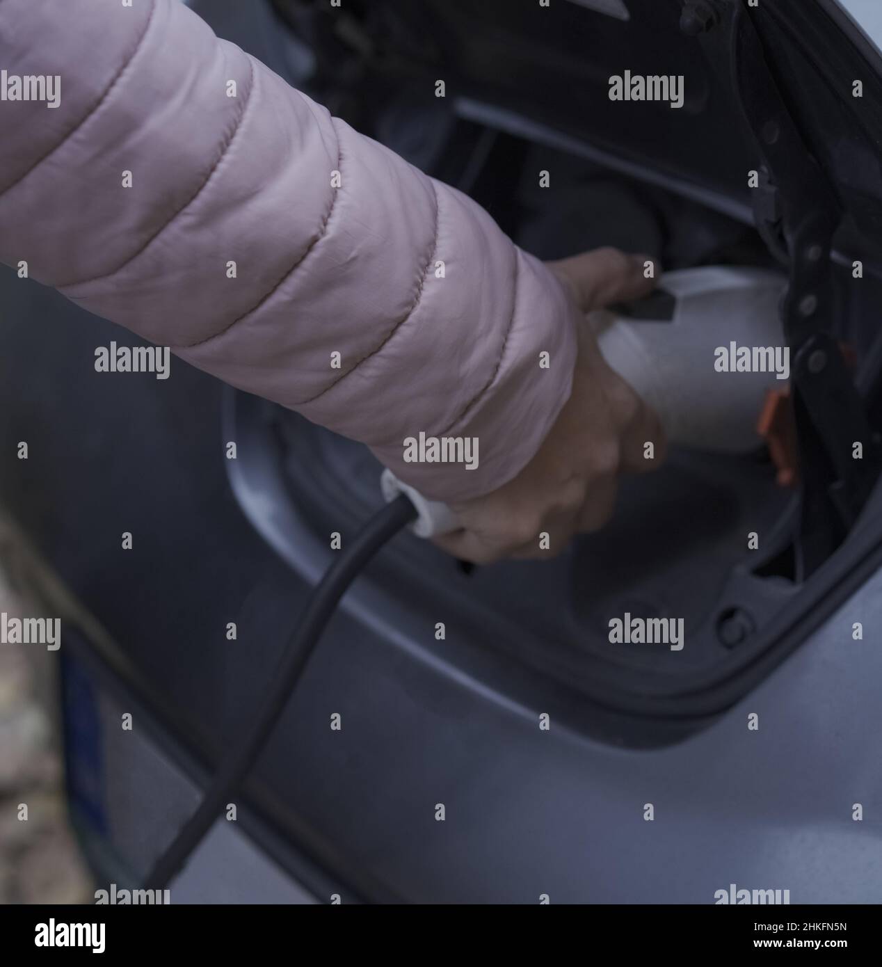 Woman charging electric car at the charge station. Voltage and Power ...