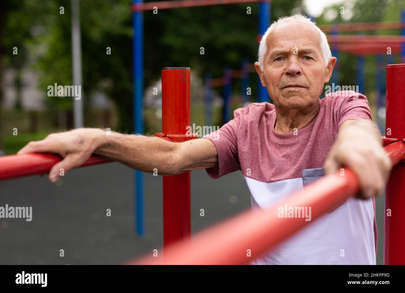 Old man standing between parallel bars outdoors Stock Photo - Alamy