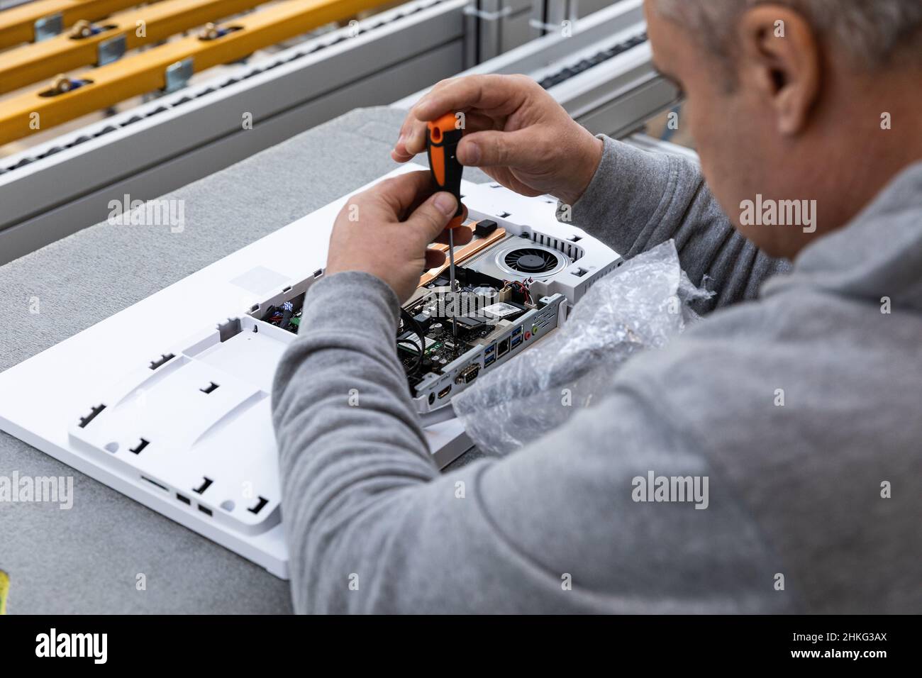 Photo of an adult man in a gray sweater who assembles a computer ...