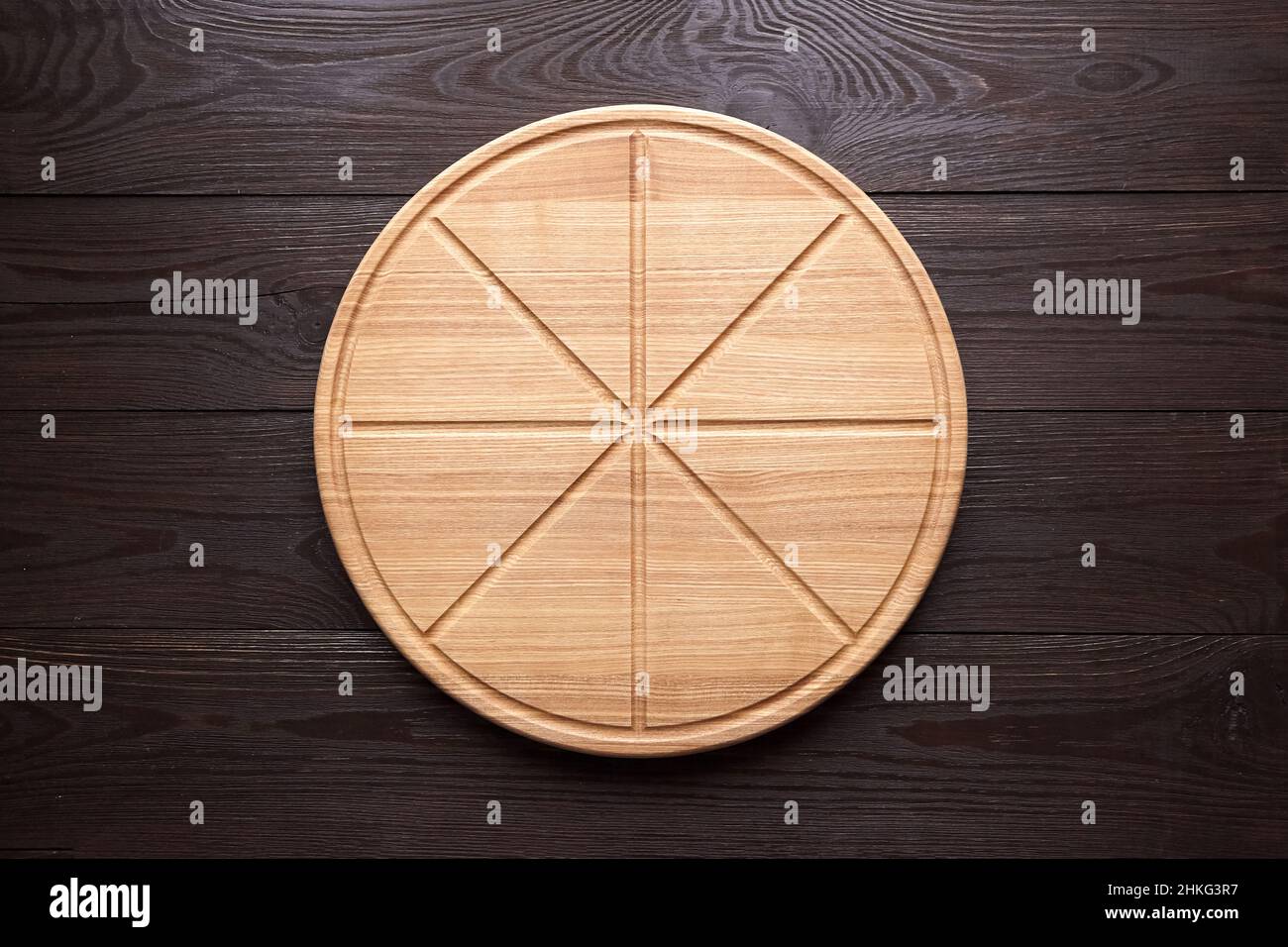 Round pizza cutting board with slice grooves on brown wooden table top ...
