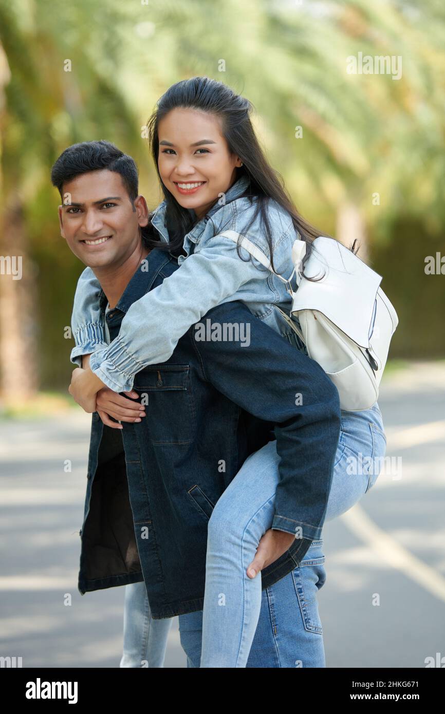 Joyful young couple enjoying spending time together in park on Sunday, man giving girlfriend ...
