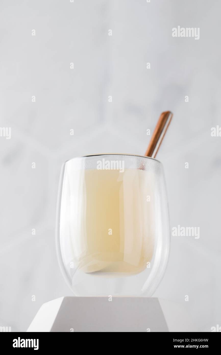 Healthy bone broth in a transparent mug on a pedestal with a spoon on a ...