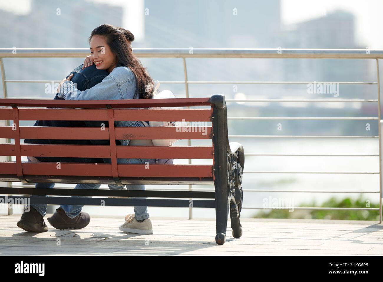 Hugging young couple sitting on bench, happy to see each other after ...