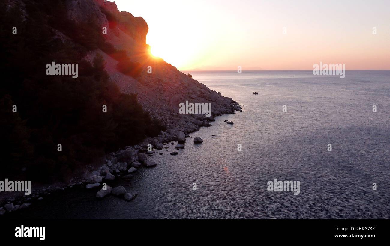 Sunrise over mountain rock in sea water. Sunrise seascape in calm sea ...
