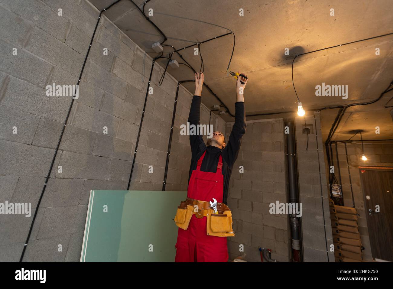 handsome young man electrician working on switchboard of house building ...