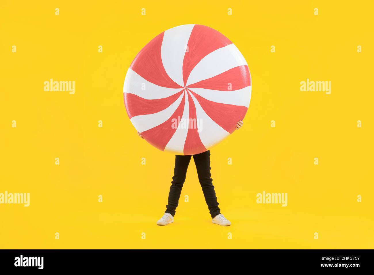 Sweetness. The girl is standing behind a huge red and white candy. Only ...