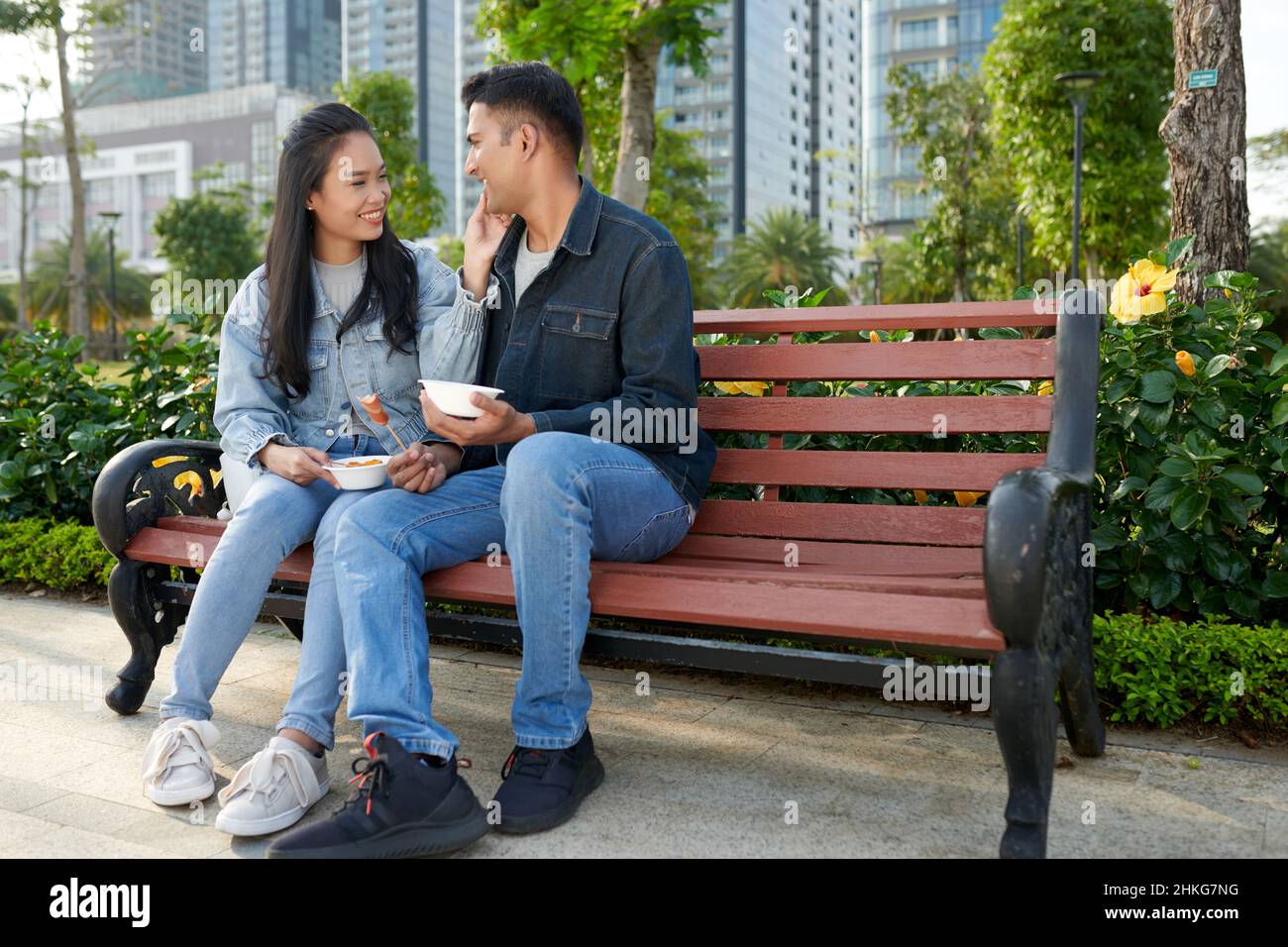 Boyfriend and girlfriend in love sitting on bench in park and eating ...