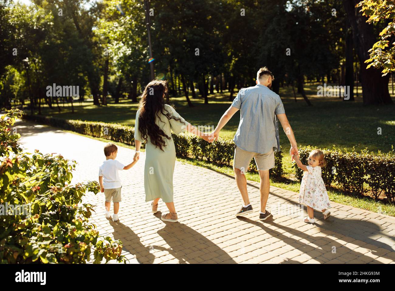 Stylish parents with small children walking at park, enjoying joyful ...