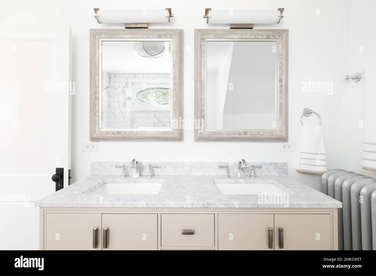 A bathroom with a cream colored double vanity cabinet, marble ...