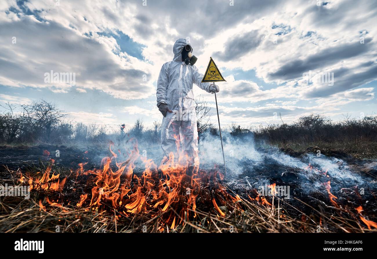 Fireman working in field with wildfire. Man in protective suit and gas ...