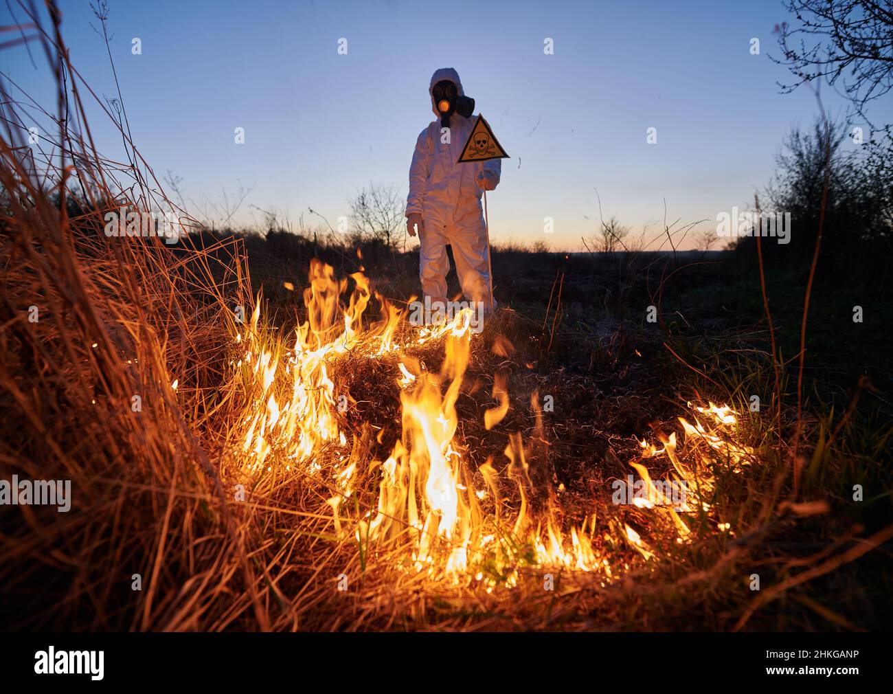 Firefighter ecologist extinguishing fire in field at night. Man in suit ...