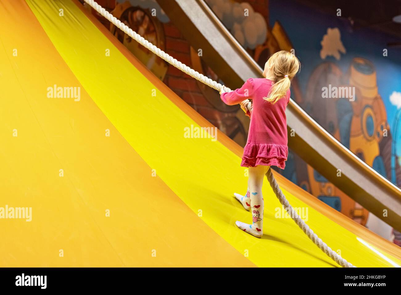 The toddler girl climbs the rope on the slide. Playground, happy ...