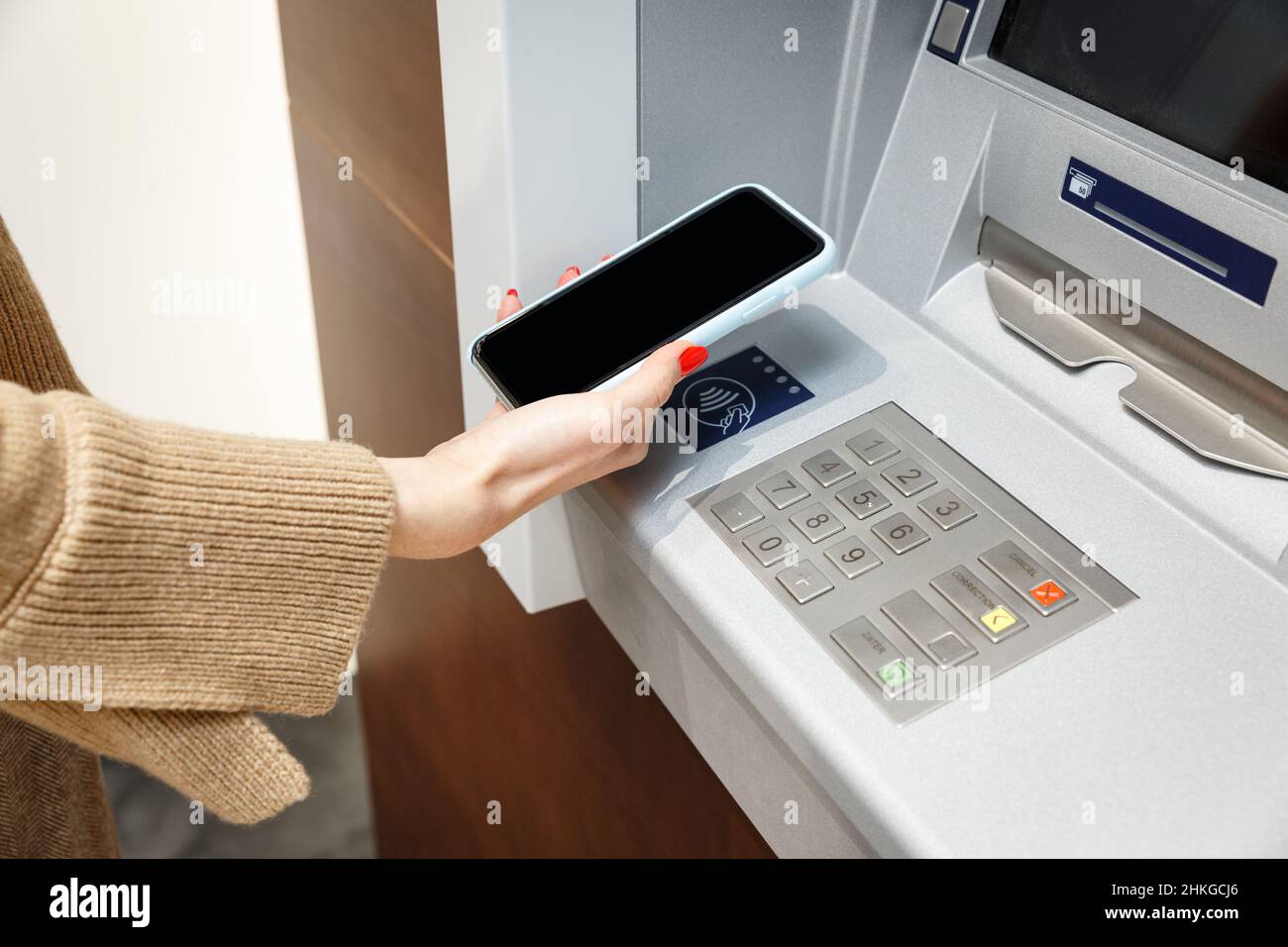Female hand with mobile phone withdrawing money from atm using NFC ...