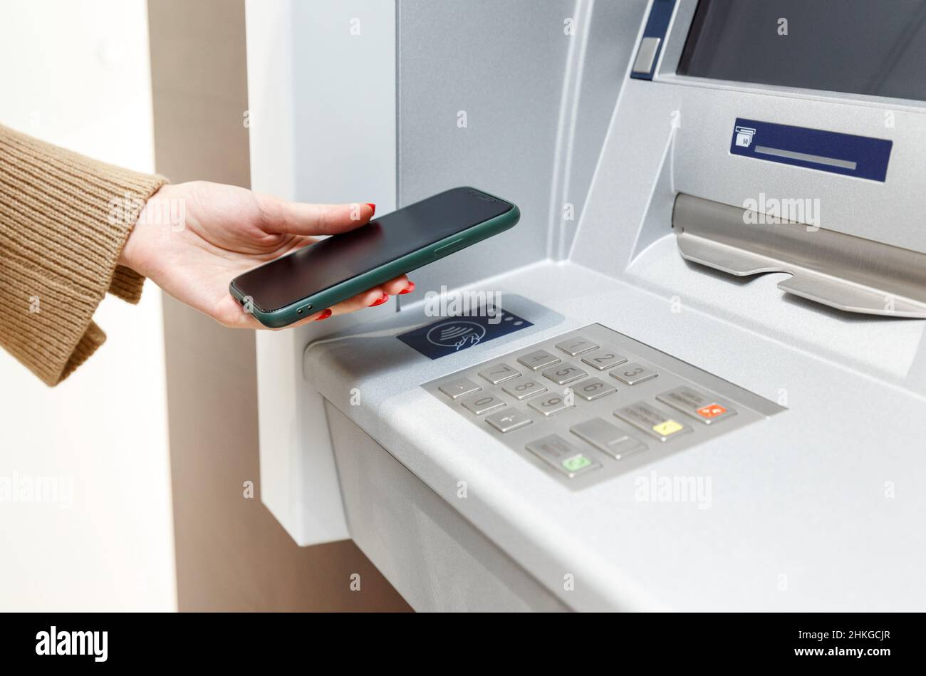 Female hand with mobile phone withdrawing money from atm using NFC ...