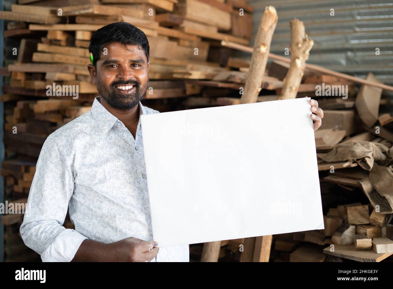Happy smiling Carpenter with white sign board looking at camera ...