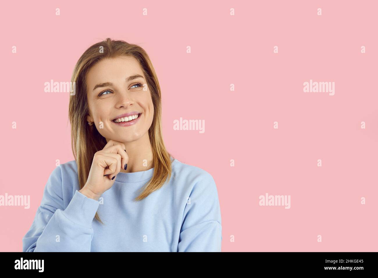 Happy young woman thinking, dreaming and imagining something on copy ...