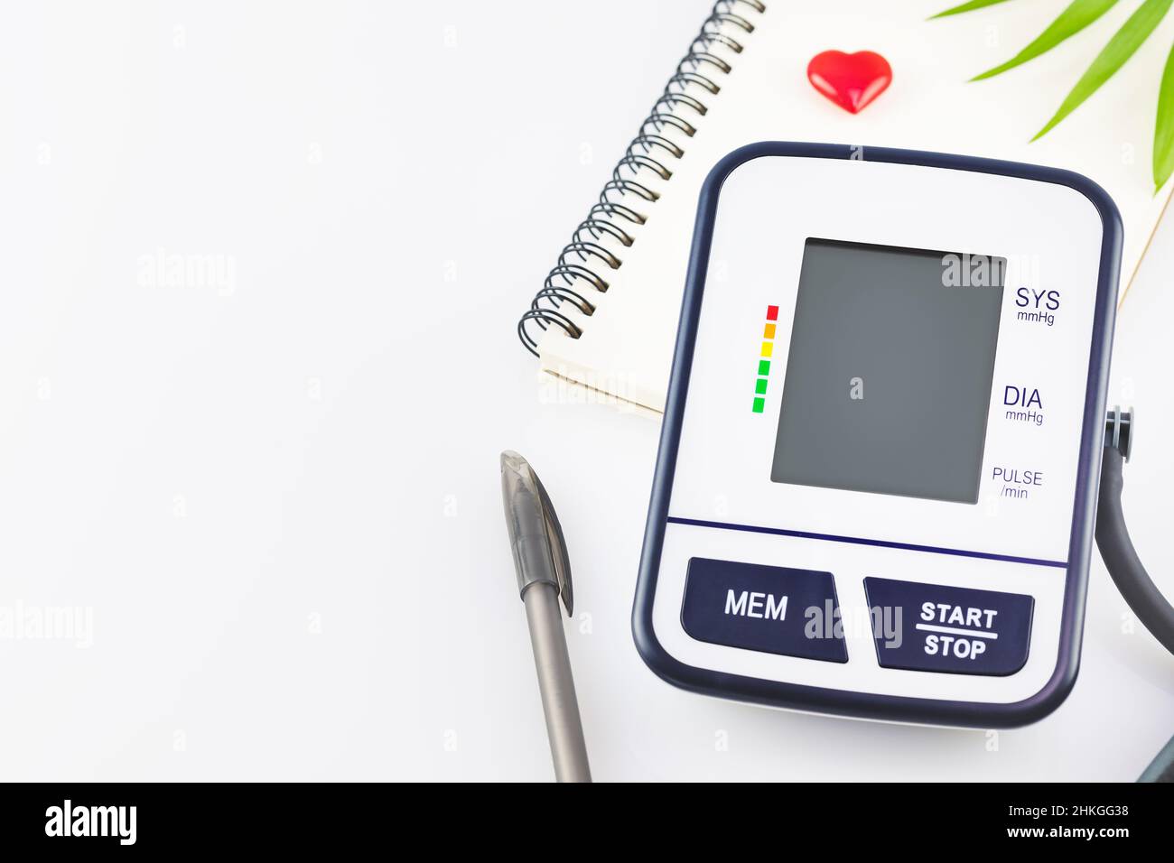 Digital blood pressure monitor, notepad, pen on a white background with ...