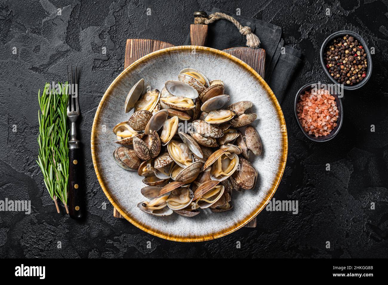Steamed cooked shells Clams vongole in a plate with herbs. Black ...