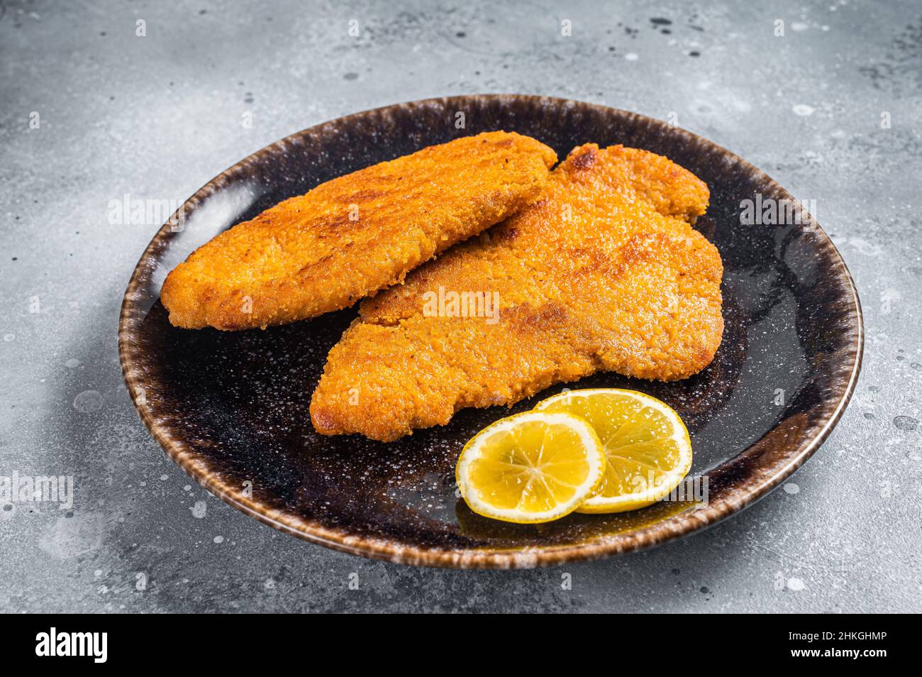 Roasted breaded german weiner schnitzel on a plate. Gray background ...