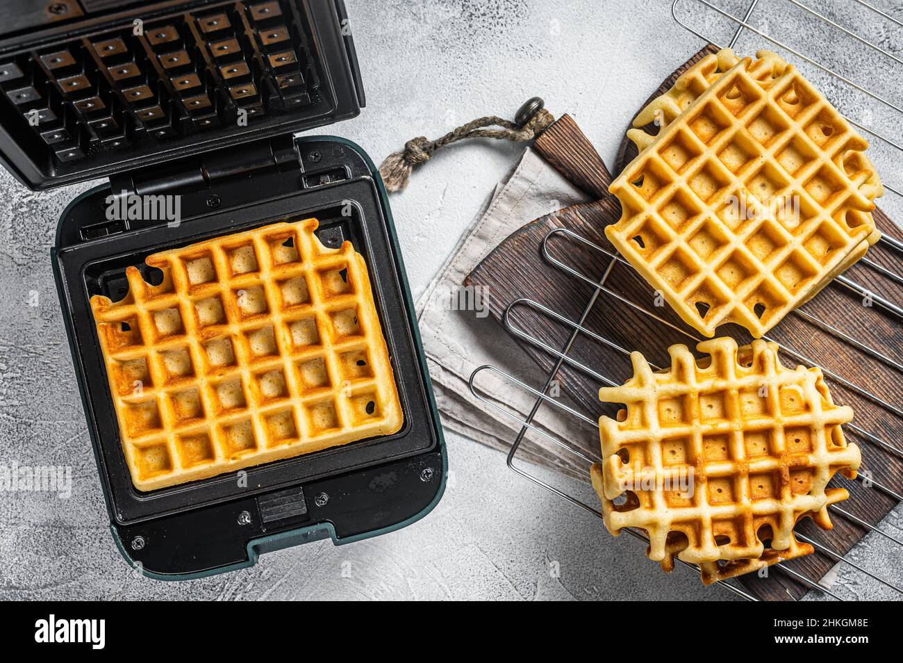 Cooking of fresh waffles in waffle maker. White background. Top view ...