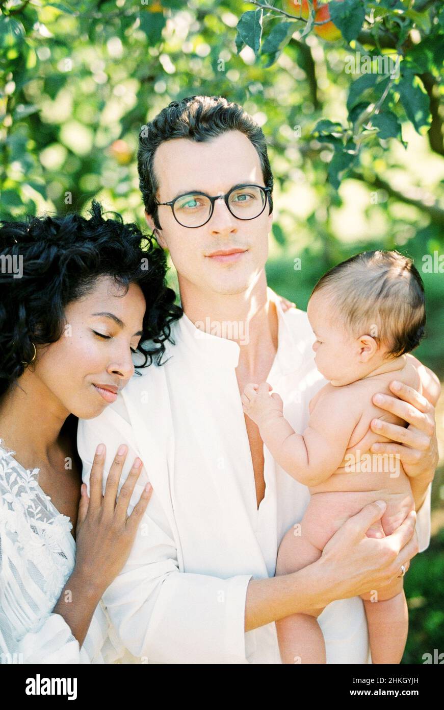 Woman hugging a man holding a newborn in his arms Stock Photo - Alamy