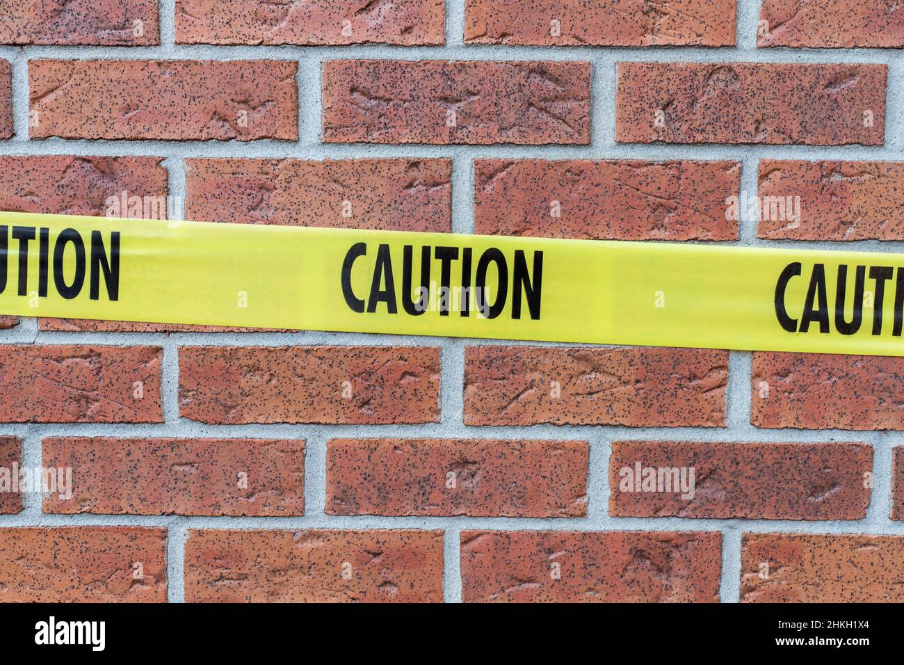 Caution yellow tape close-up against red brick wall Stock Photo - Alamy