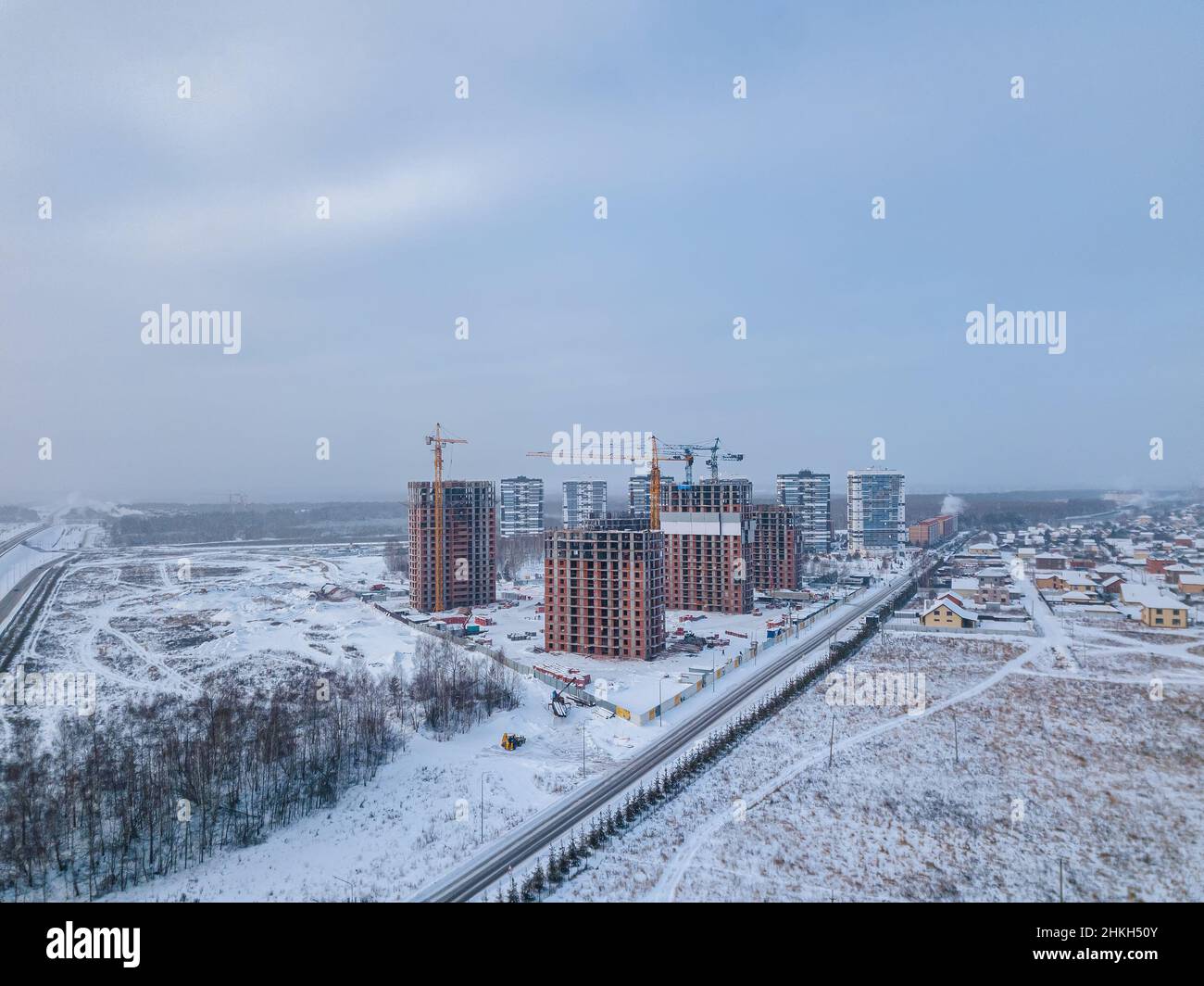 Construction cranes and houses under construction. Construction of a ...