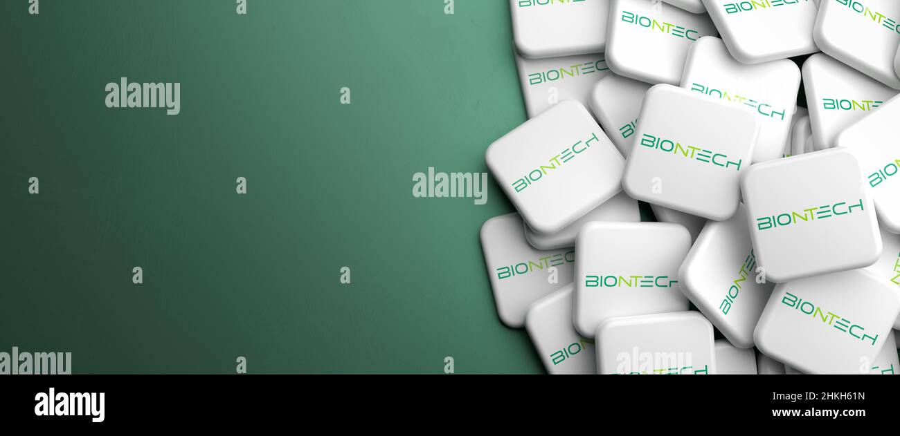 Logos of the German biotechnology company BioNTech on a heap on a table ...
