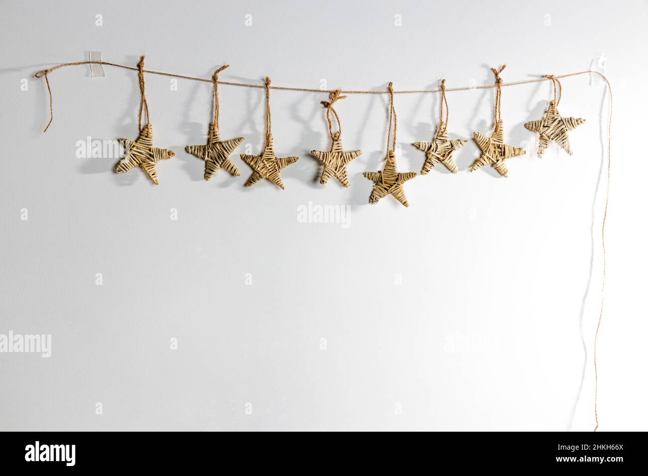 A handmade garland of braided stars is on a white wall. Place for text ...