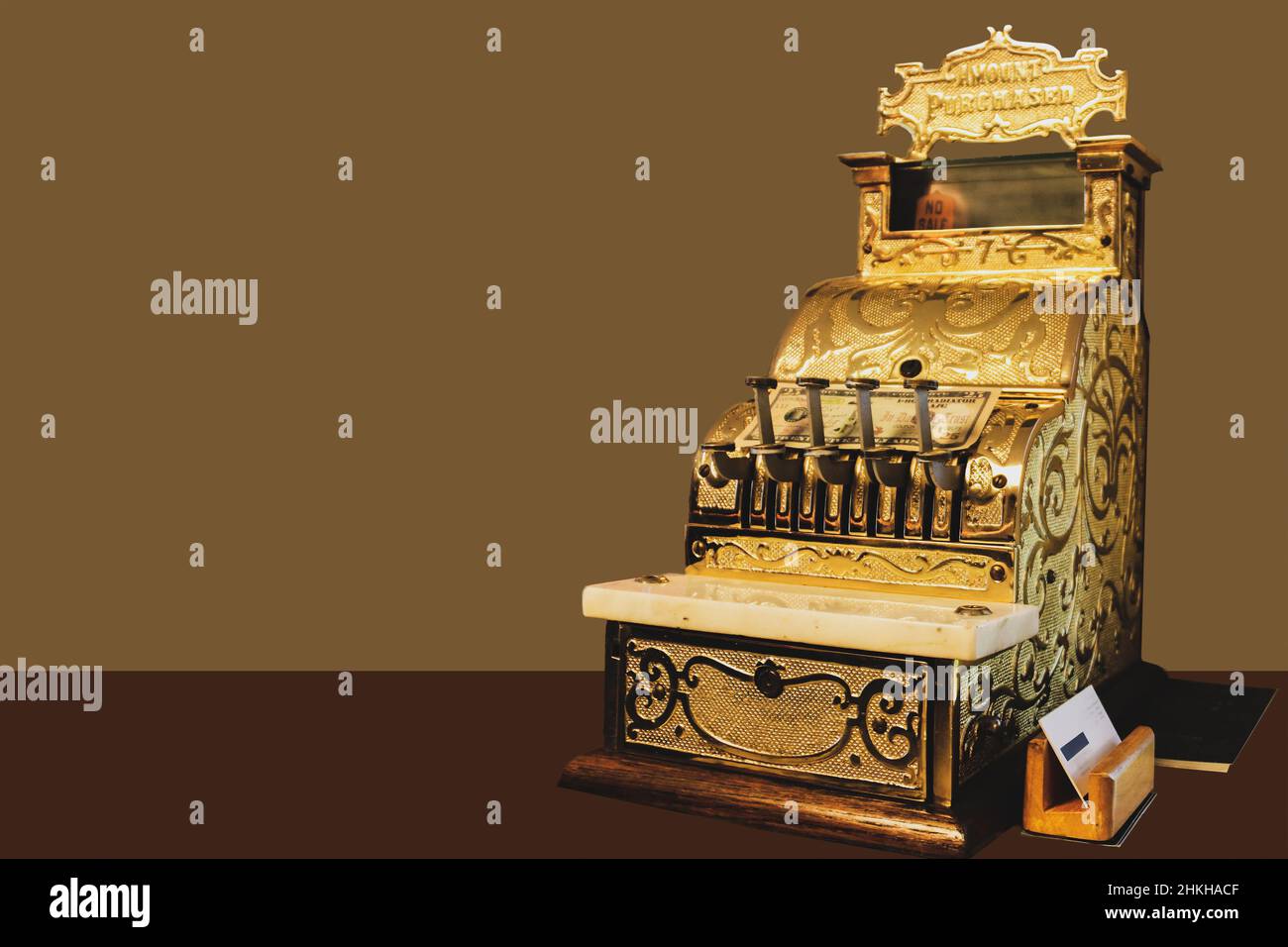 Fancy golden ornate cash register on counter with bill laid on it and ...