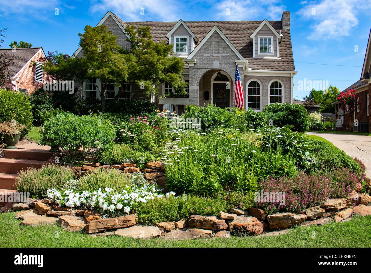 Grey multiple gable brick house with colorful rock garden in front ...