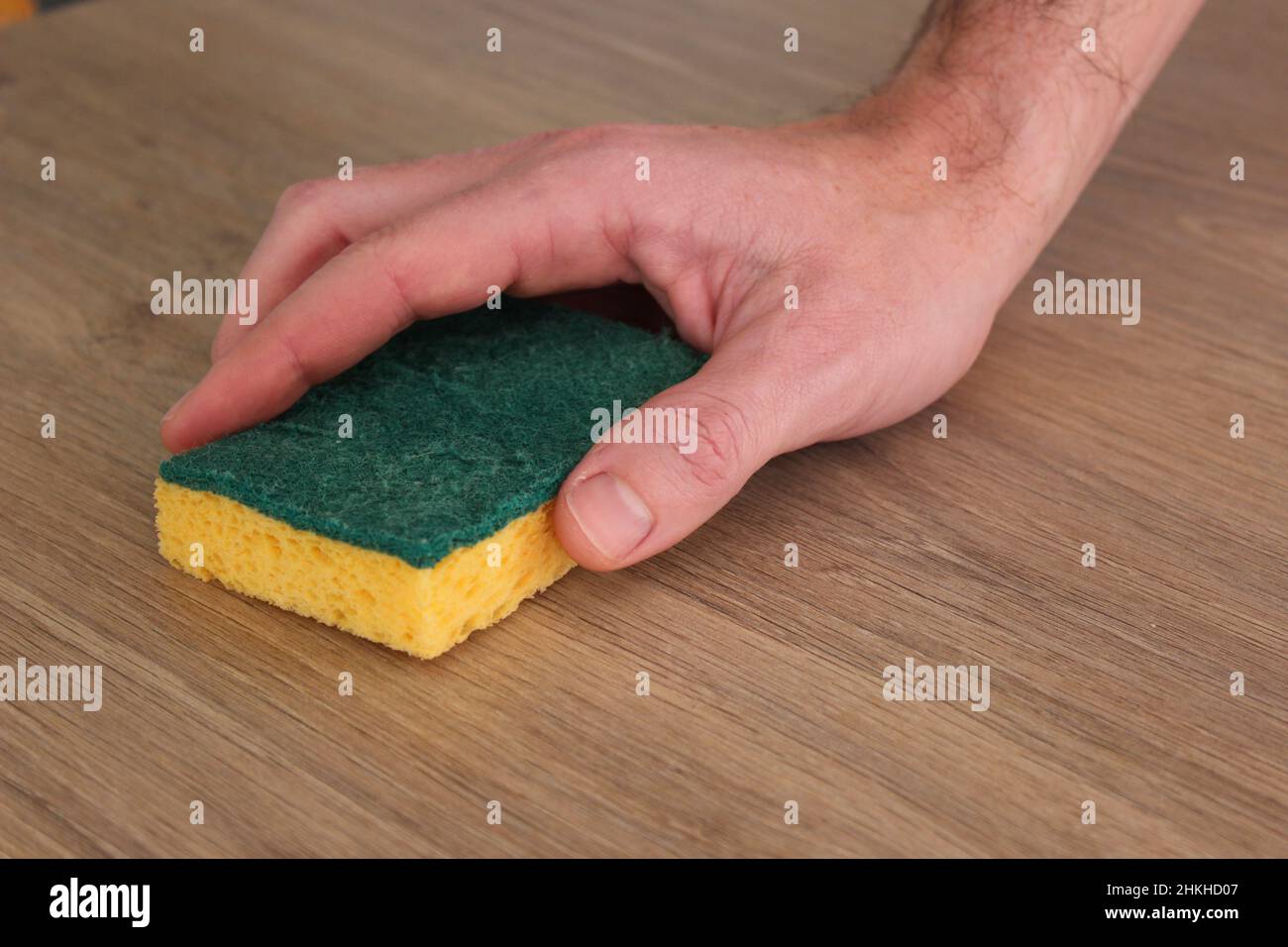Man's hand washing a table with a sponge Stock Photo - Alamy