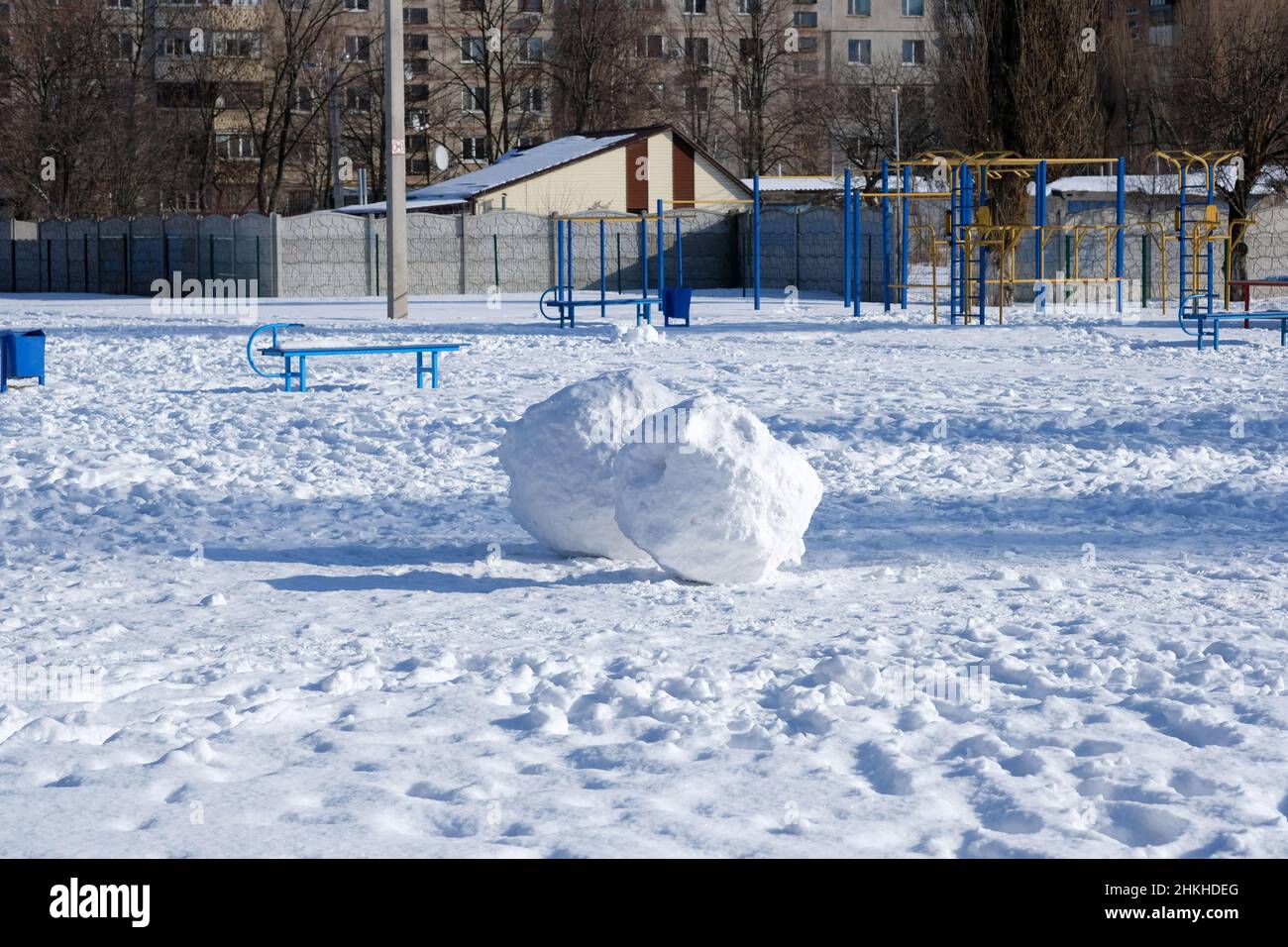 Two balls of snow on the playground in the yard. Sunny day in winter in ...