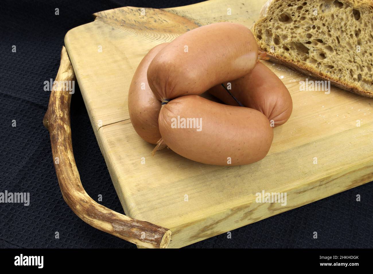 small sausage on a cutting board close-up. Sausages with bread. Pork ...
