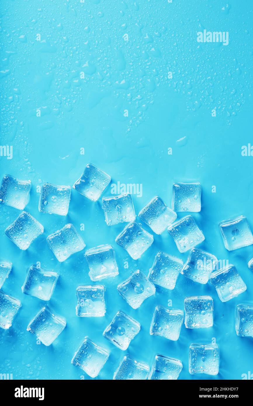 Ice cubes with water drops scattered on a blue background, top view ...