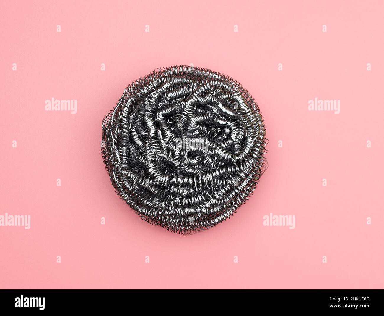Metal scraper for dishes on a pink background top view. Stainless metal ...