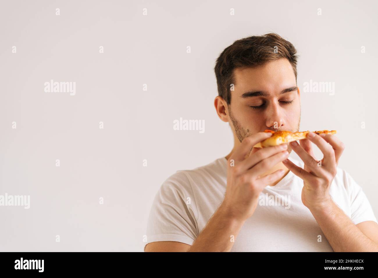 Close-up face of hungry young man enjoying sniffing slice of pizza and ...