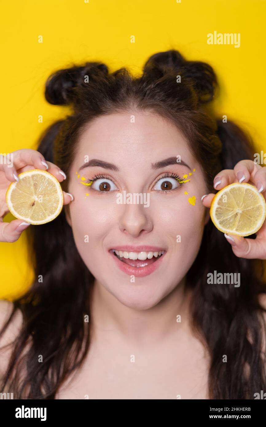 brunette woman girl with lemon near skin face on yellow background ...