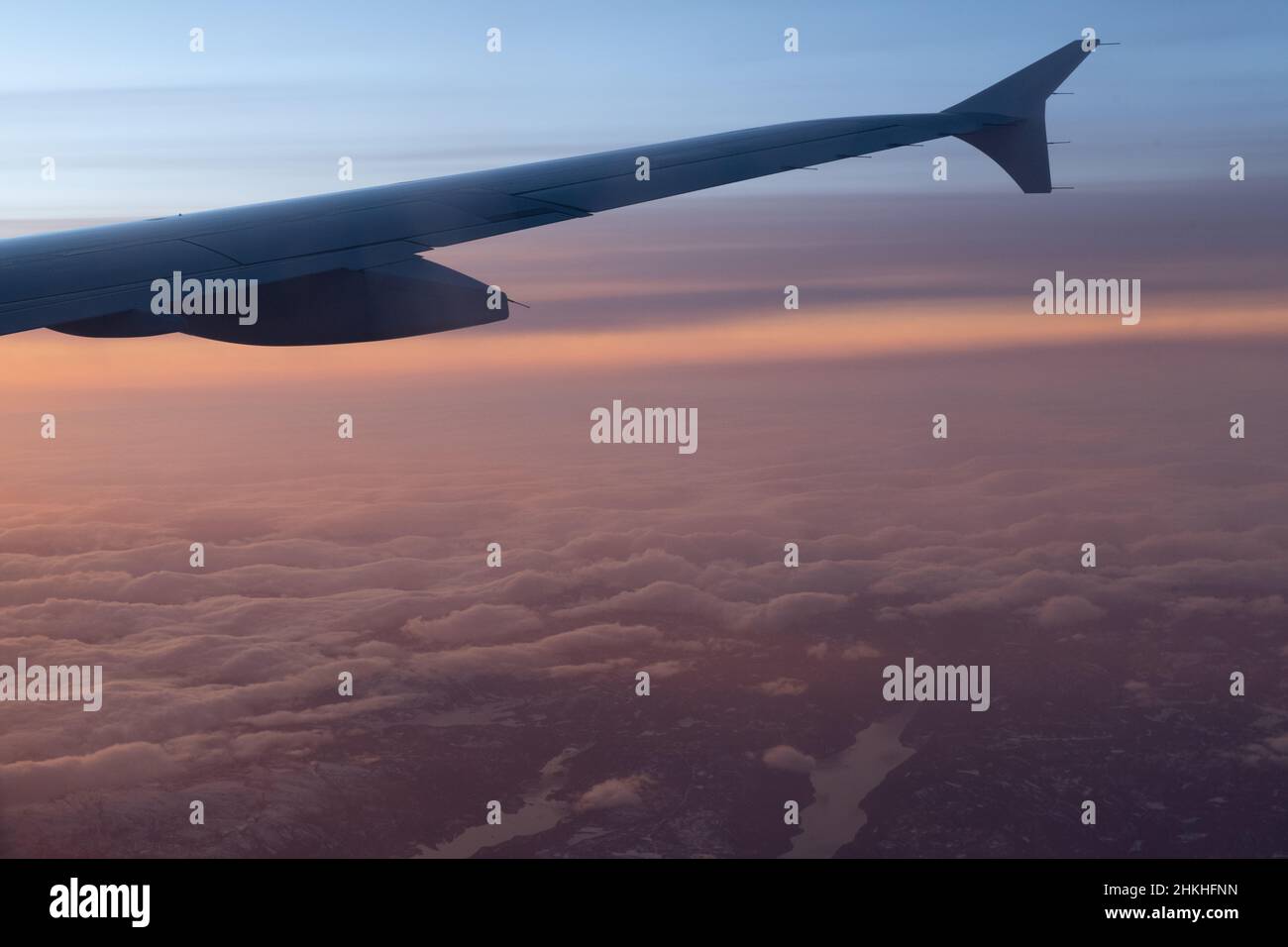 Passenger view of plane wing over pink sunset clouds, Lapland, Finland ...