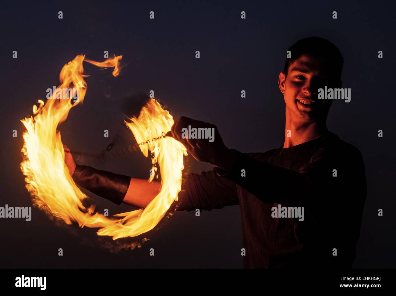 Game of light and dark. Fire spinner at night. Happy male spinner spin ...