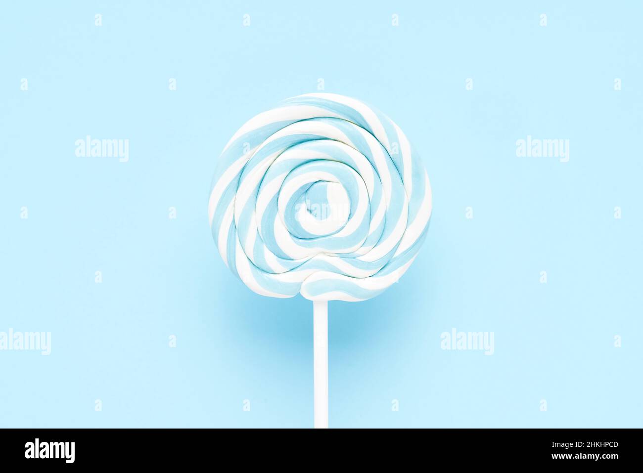 Blue-white lollipop on a white stick on a light blue background. Top ...