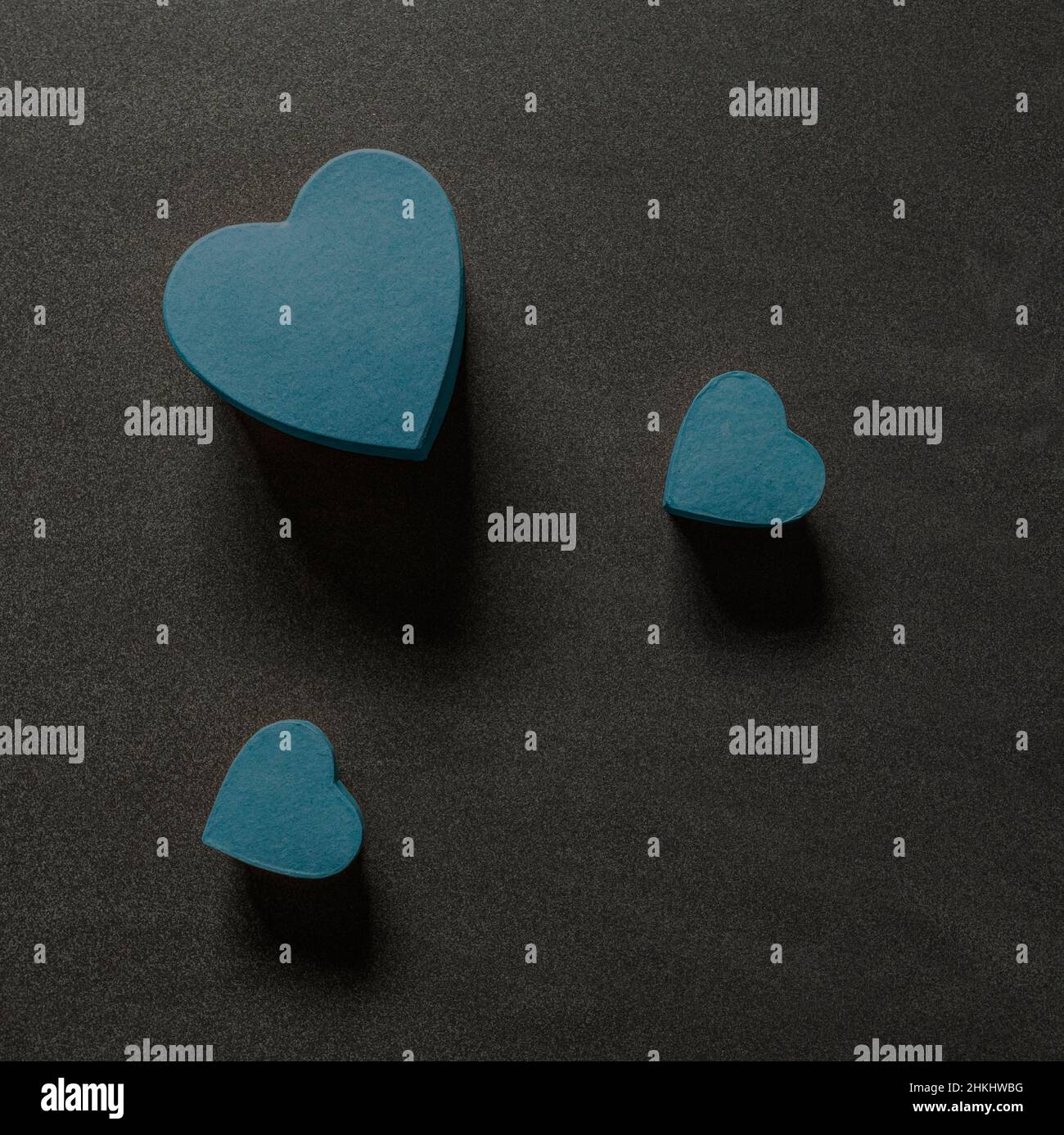 three blue heart shapes on a black background from above Stock Photo ...