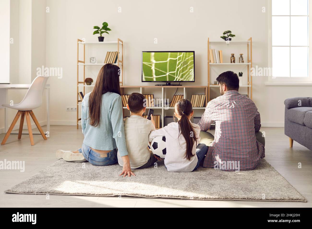 Family with children watching football match together at home cheering ...