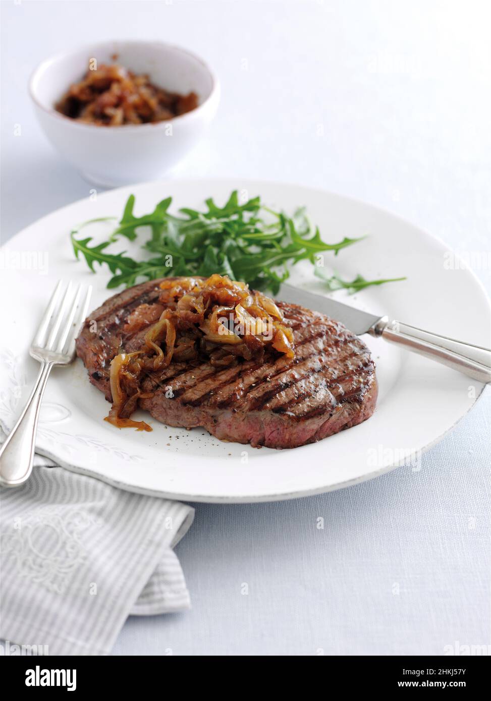 Grilled steak with onion marmalade and rocket garnish Stock Photo - Alamy