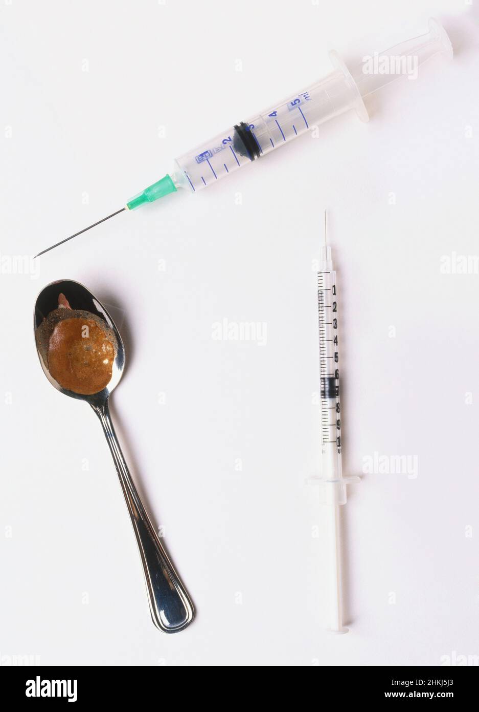 Two syringes and a spoon containing brown substance Stock Photo - Alamy