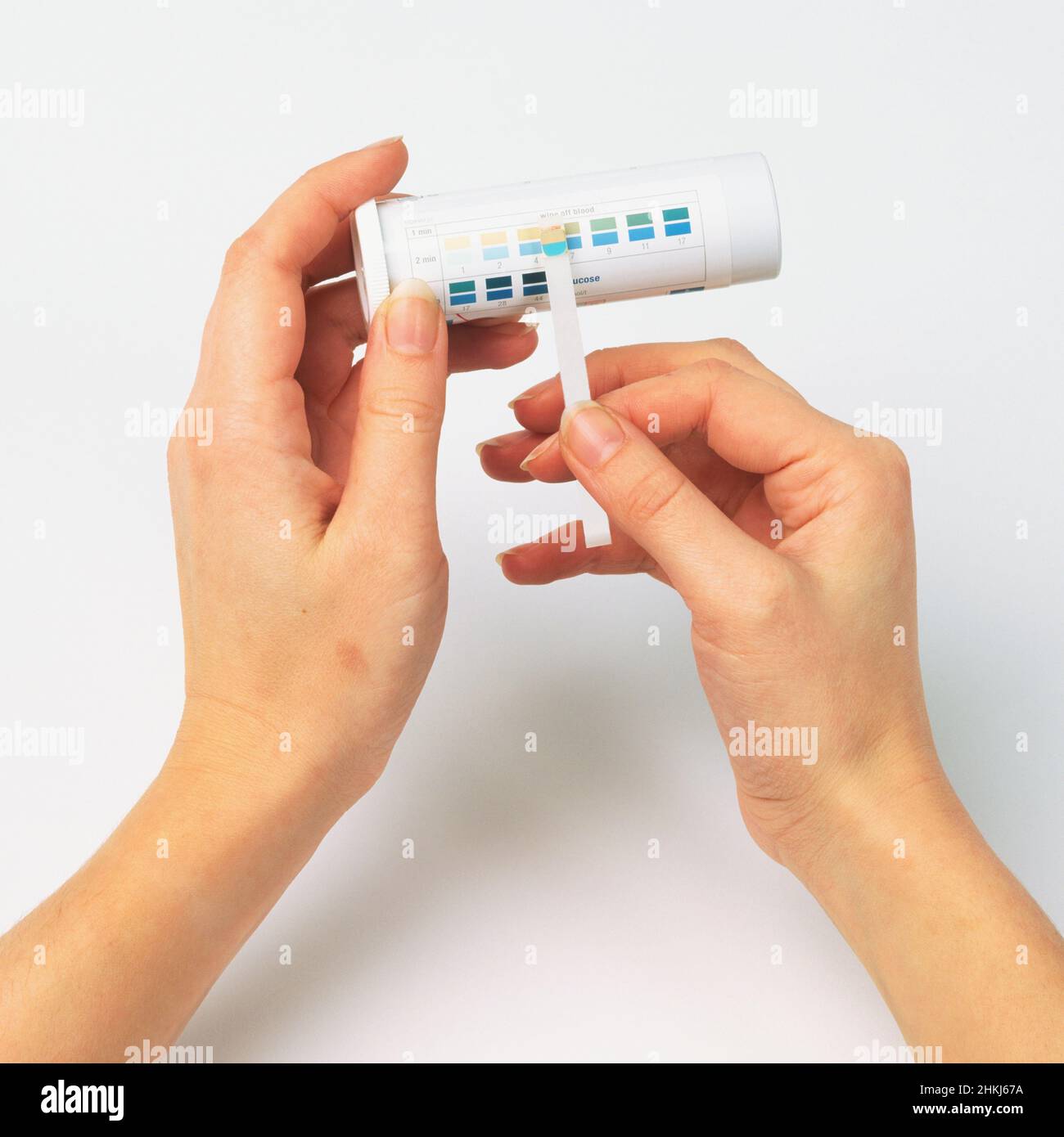 Holding paper against colour chart testing for glucose Stock Photo - Alamy