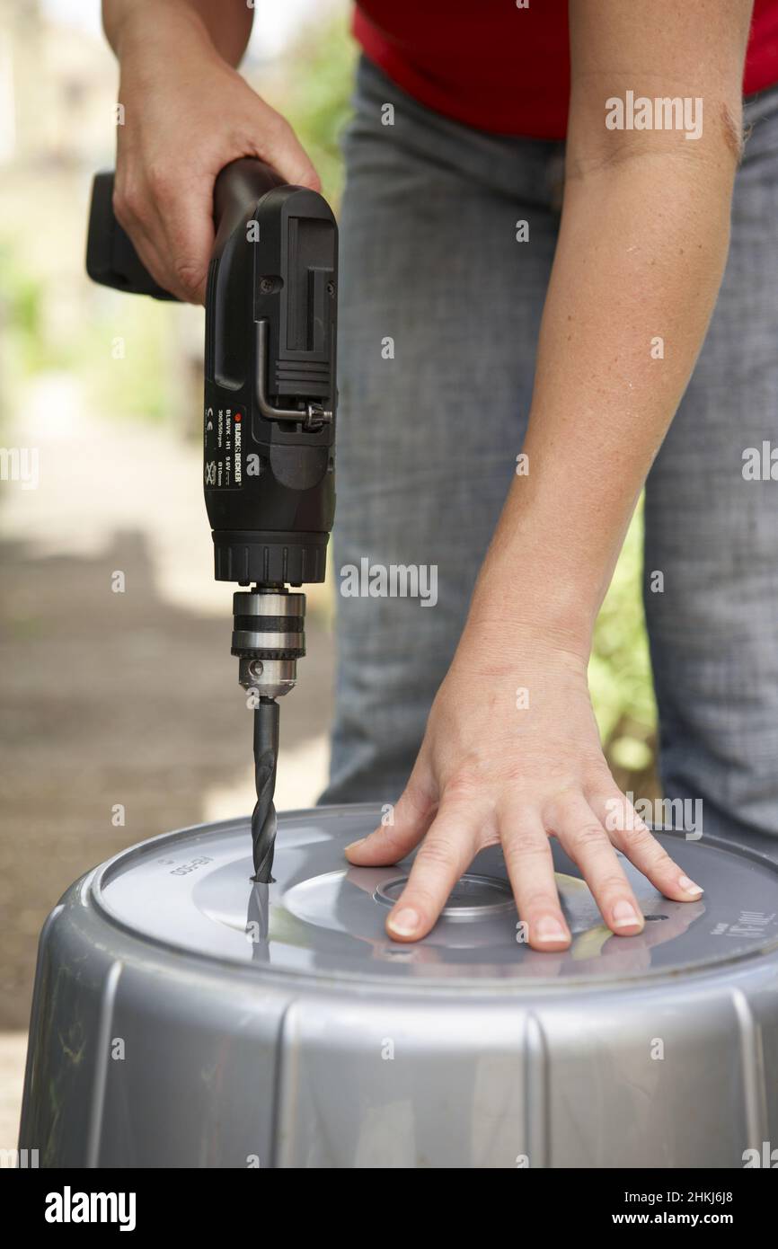 Making holes in base of plastic bin with electric drill Stock Photo - Alamy