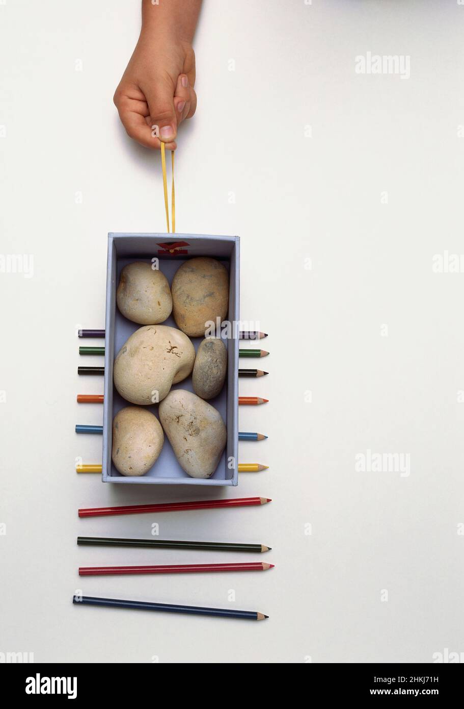 Person pulling pebble-filled box over pencils Stock Photo - Alamy