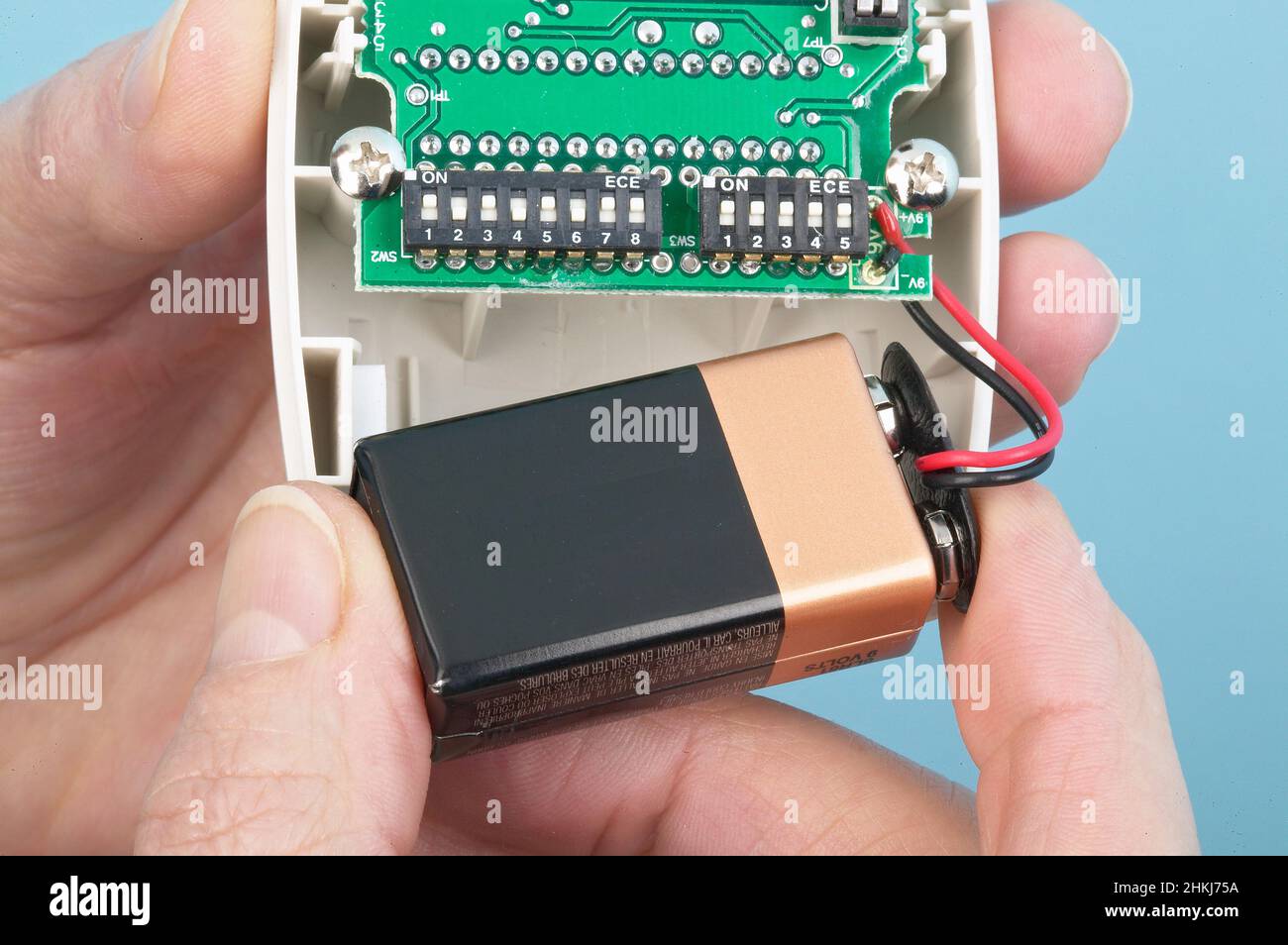Inserting battery into a passive infrared sensor Stock Photo - Alamy